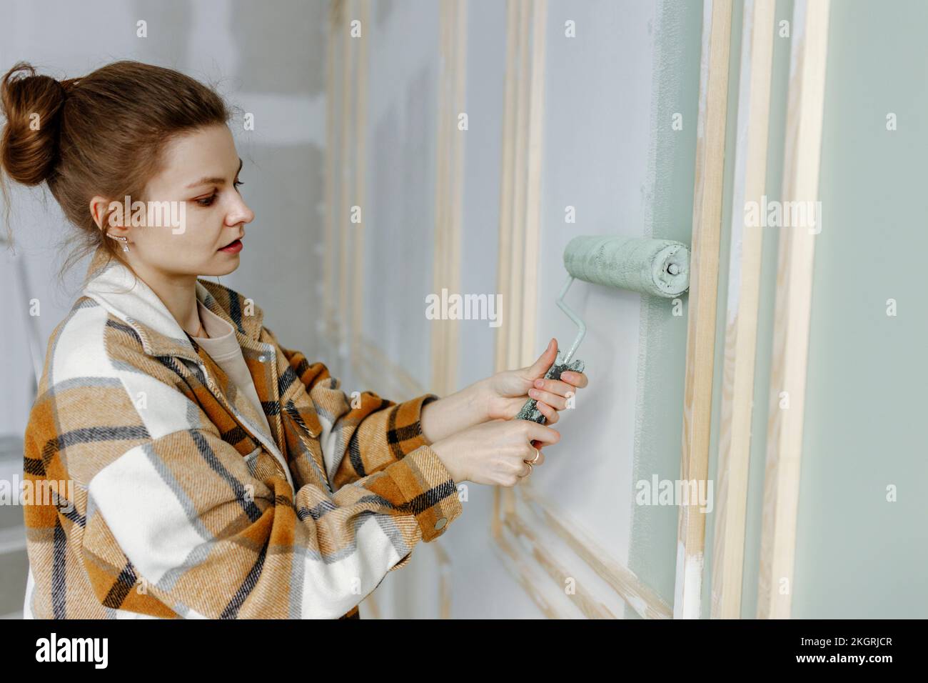 Young woman applying paint on wall renovating home Stock Photo - Alamy