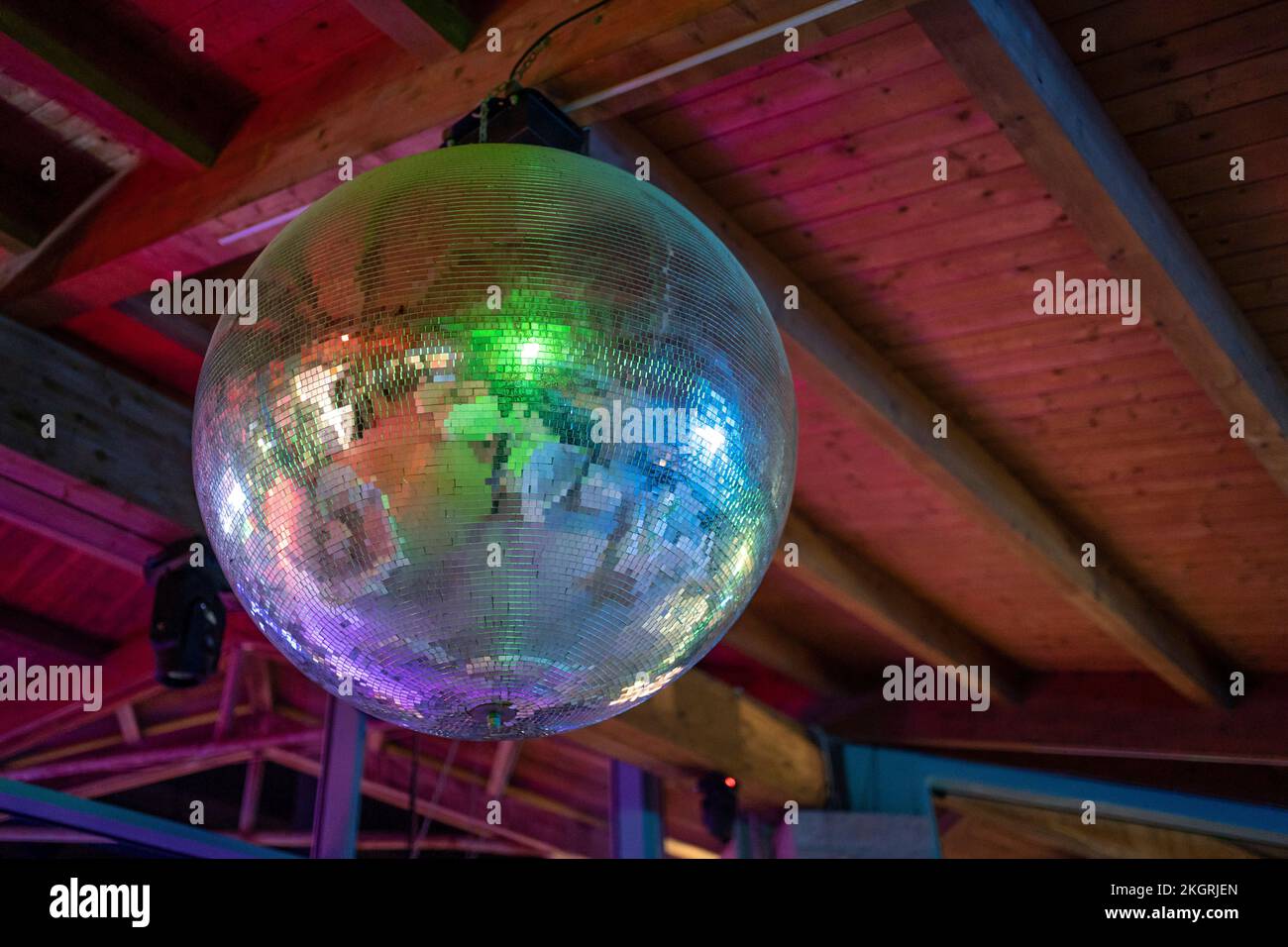 A large disco mirror ball reflecting colorful lights hanging from a ...