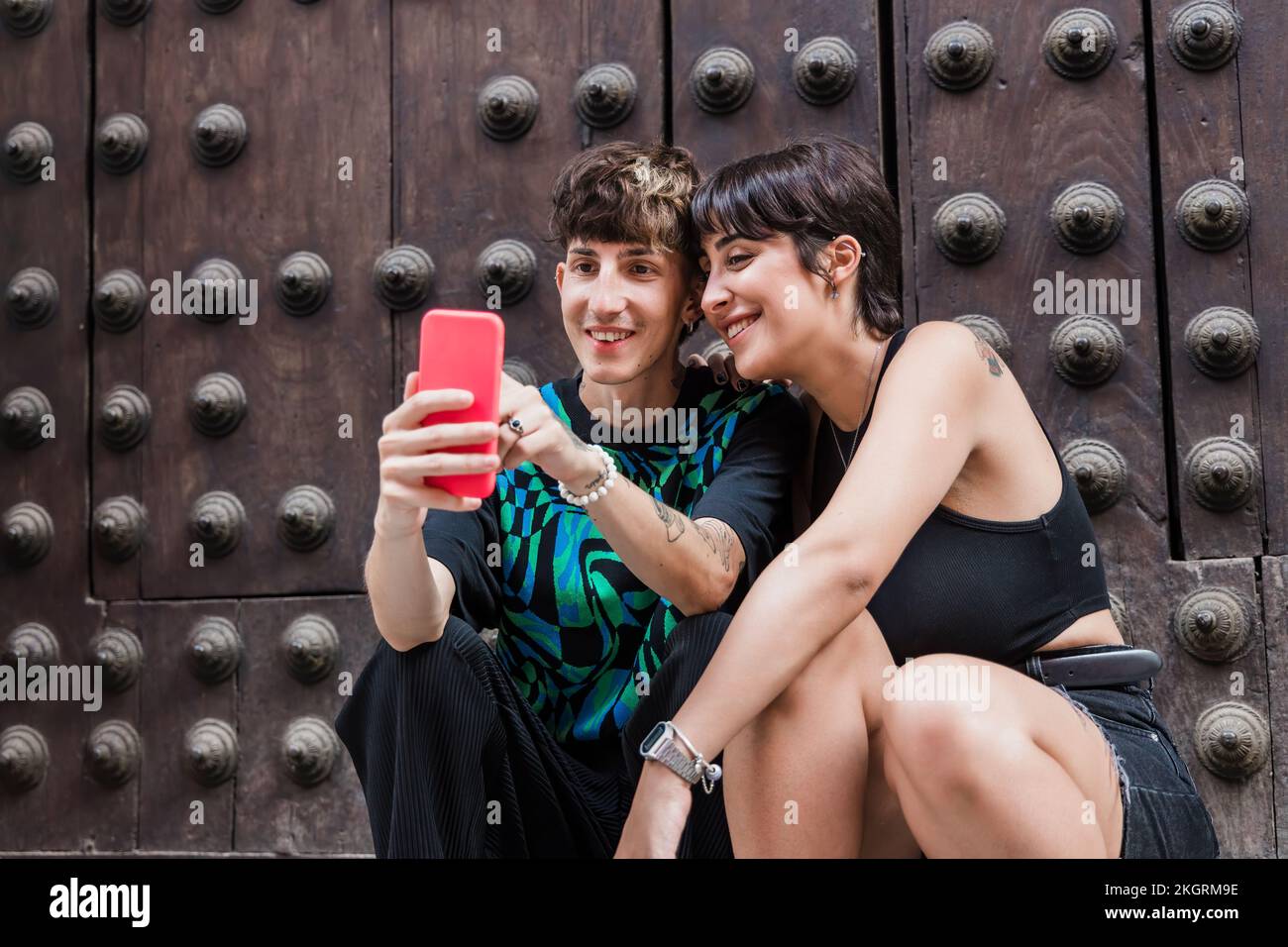 Happy man sharing mobile phone with girlfriend in front of door Stock ...
