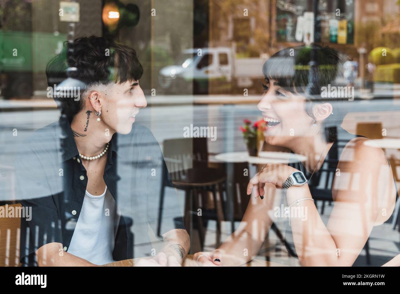 Happy young couple talking in cafe seen through glass Stock Photo - Alamy