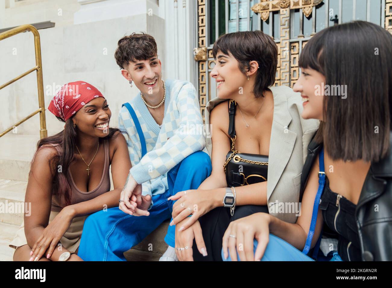 Happy friends talking with each other on staircase in front of door ...
