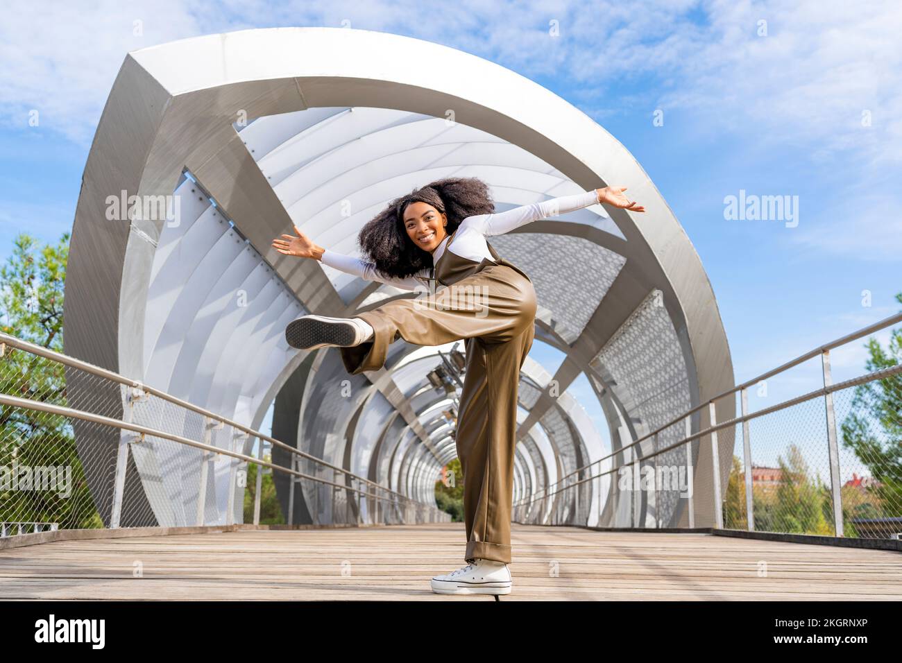 Smiling young woman dancing on bridge Stock Photo - Alamy