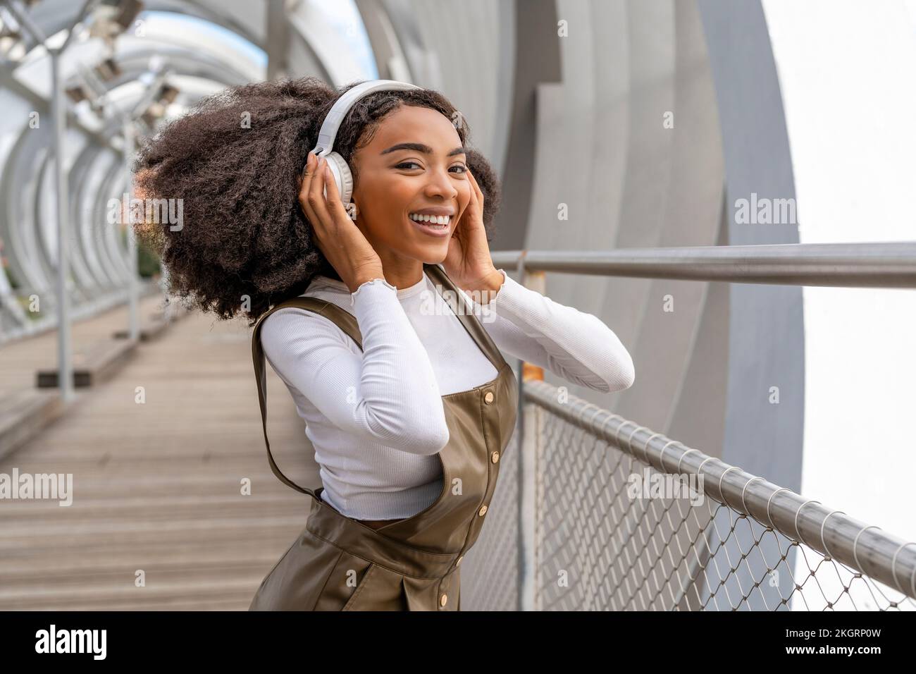 Woman listening music through bluetooth headphones on bridge Stock ...