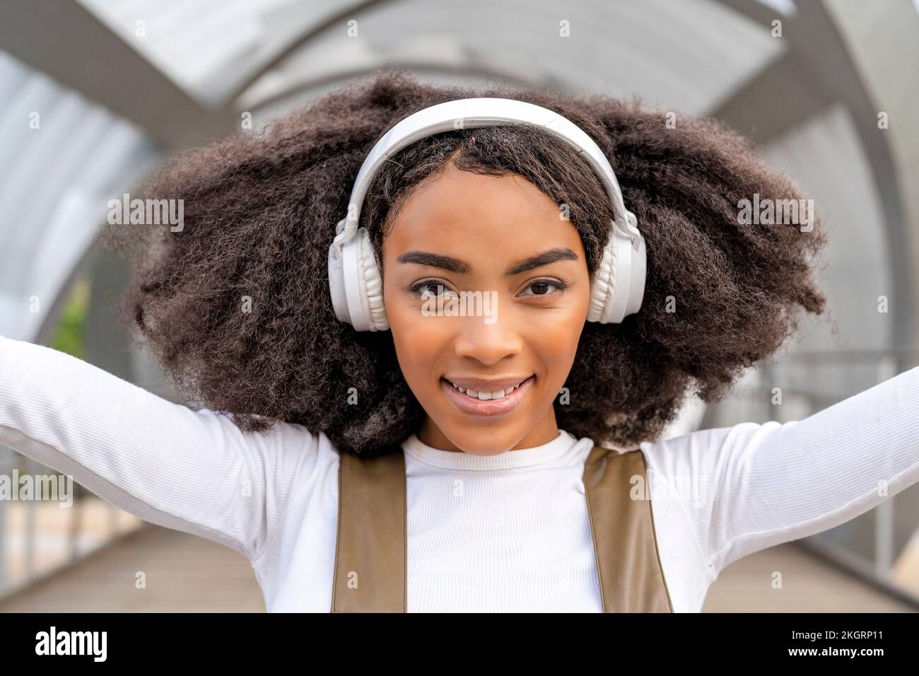 Woman with curly hair wearing bluetooth headphones Stock Photo - Alamy