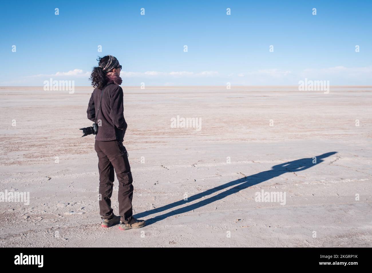 She thoughtfully stares at the horizon while holding her camera on the ...