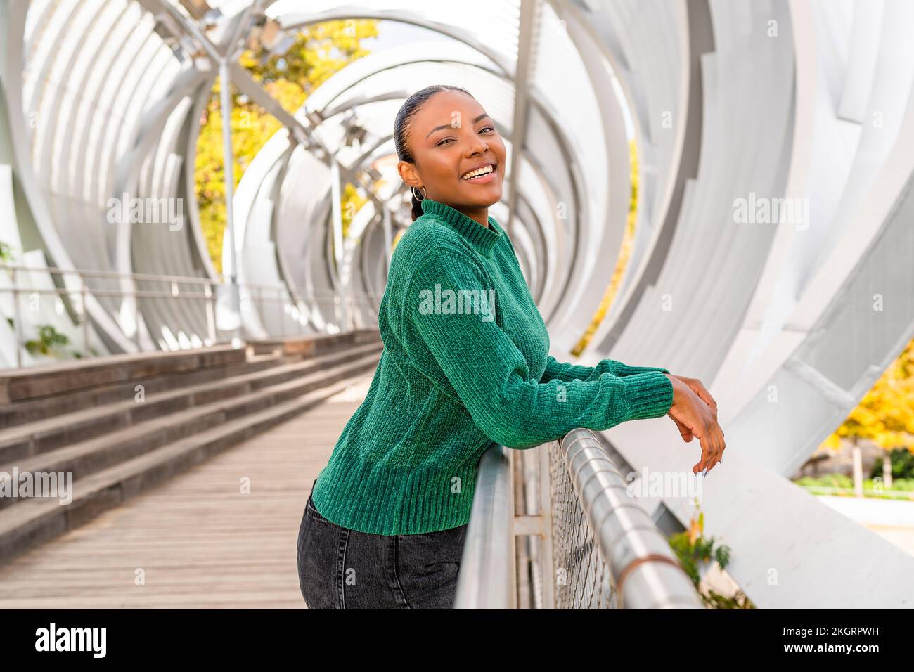 Happy young woman leaning on railing at bridge Stock Photo - Alamy