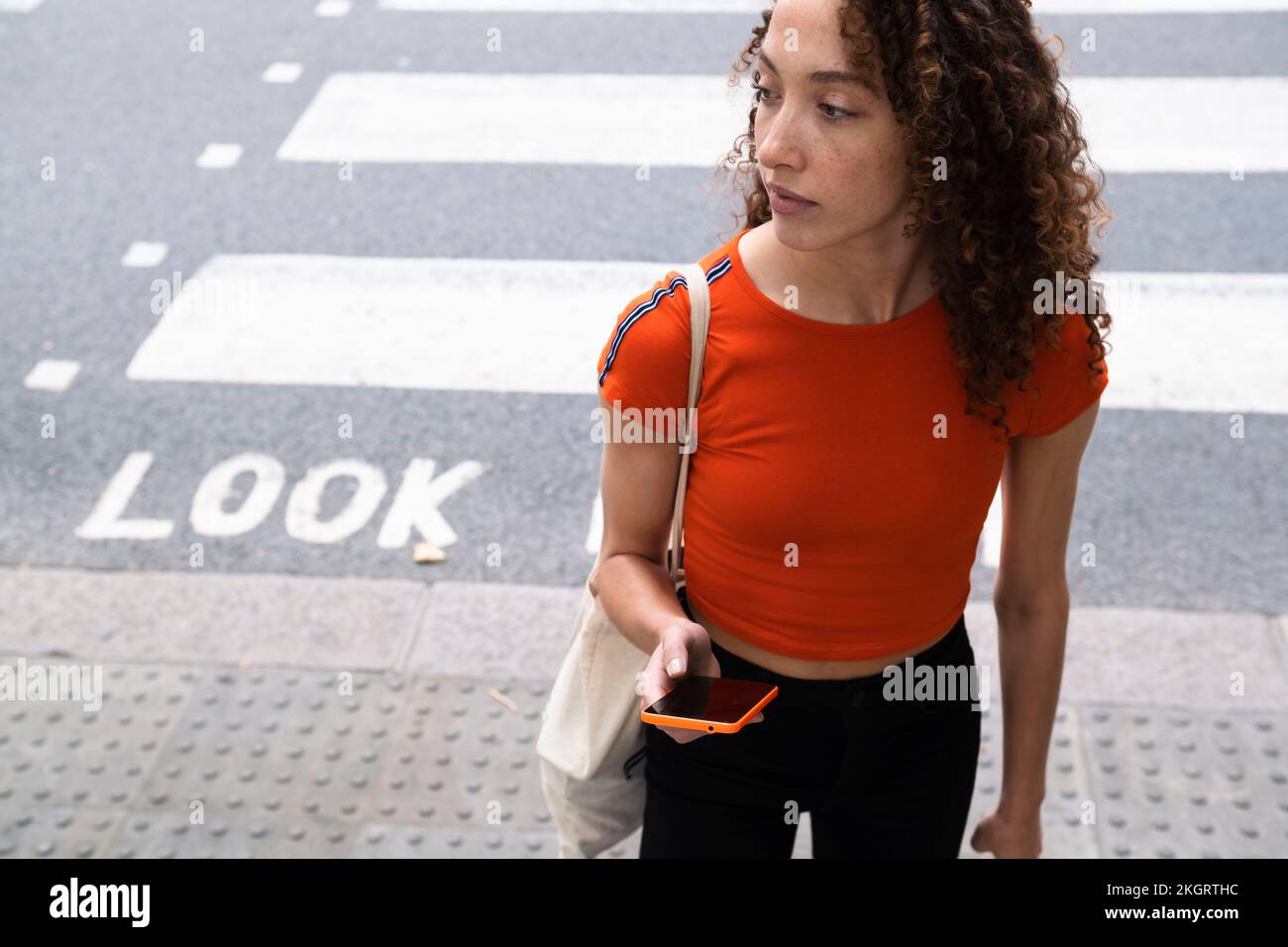 Young woman with smart phone crossing road Stock Photo - Alamy
