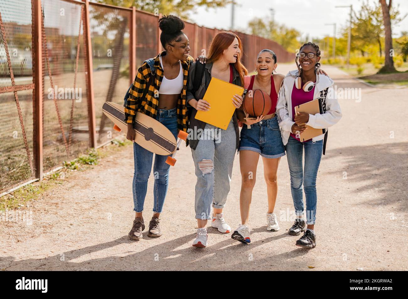 Happy friends with arms around walking together on road Stock Photo - Alamy