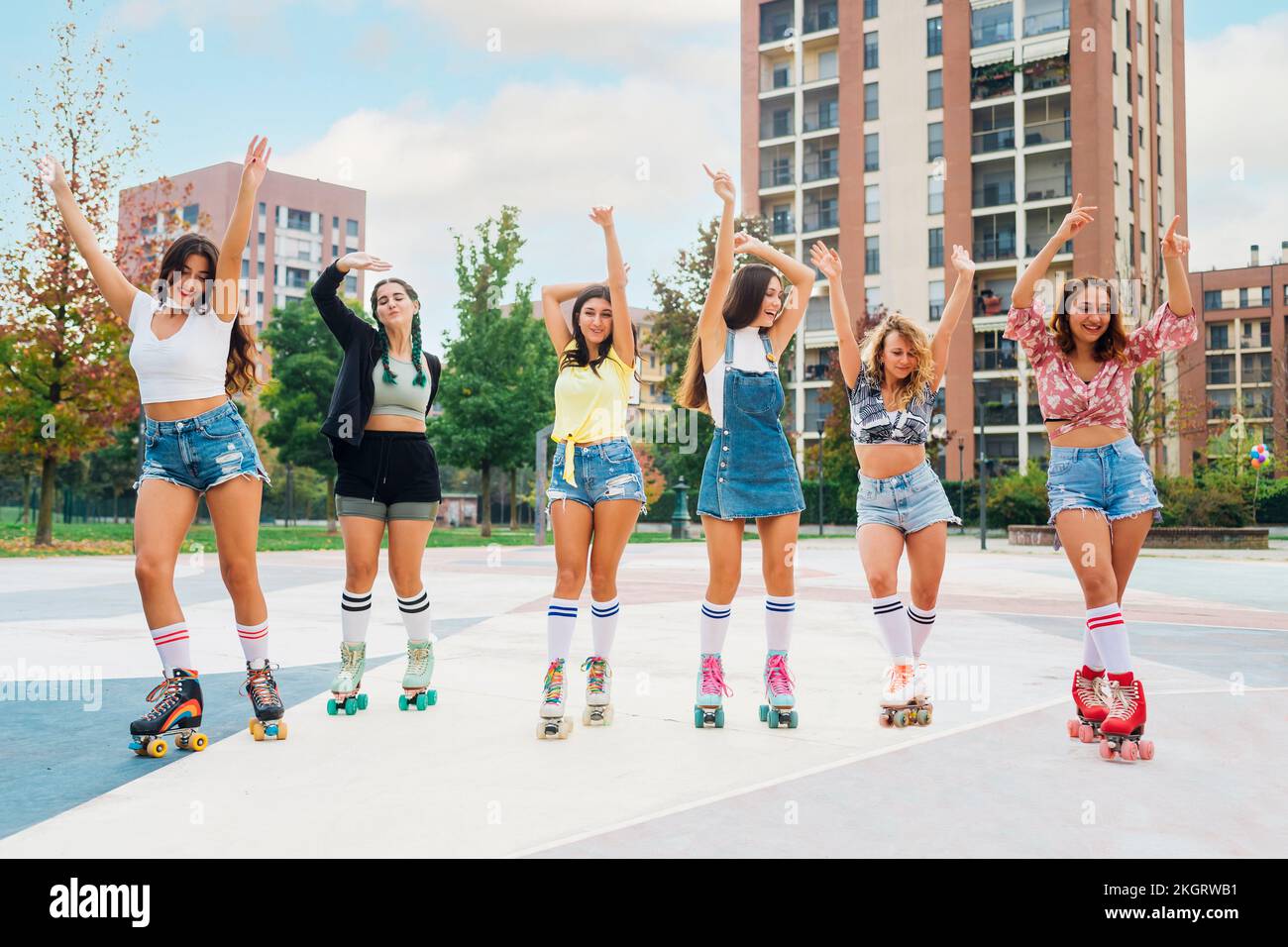 Happy friends dancing and roller skating together in sports court Stock ...