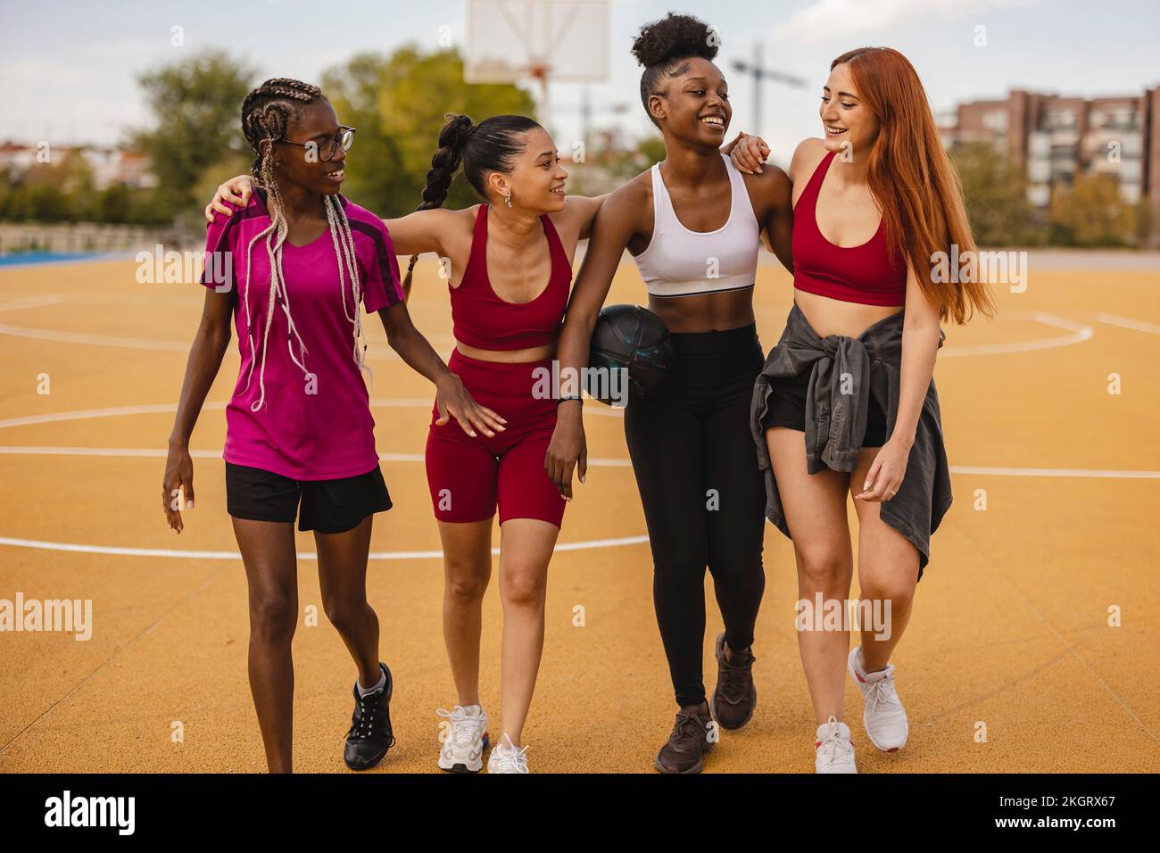 Happy young friends walking together in basketball court Stock Photo ...