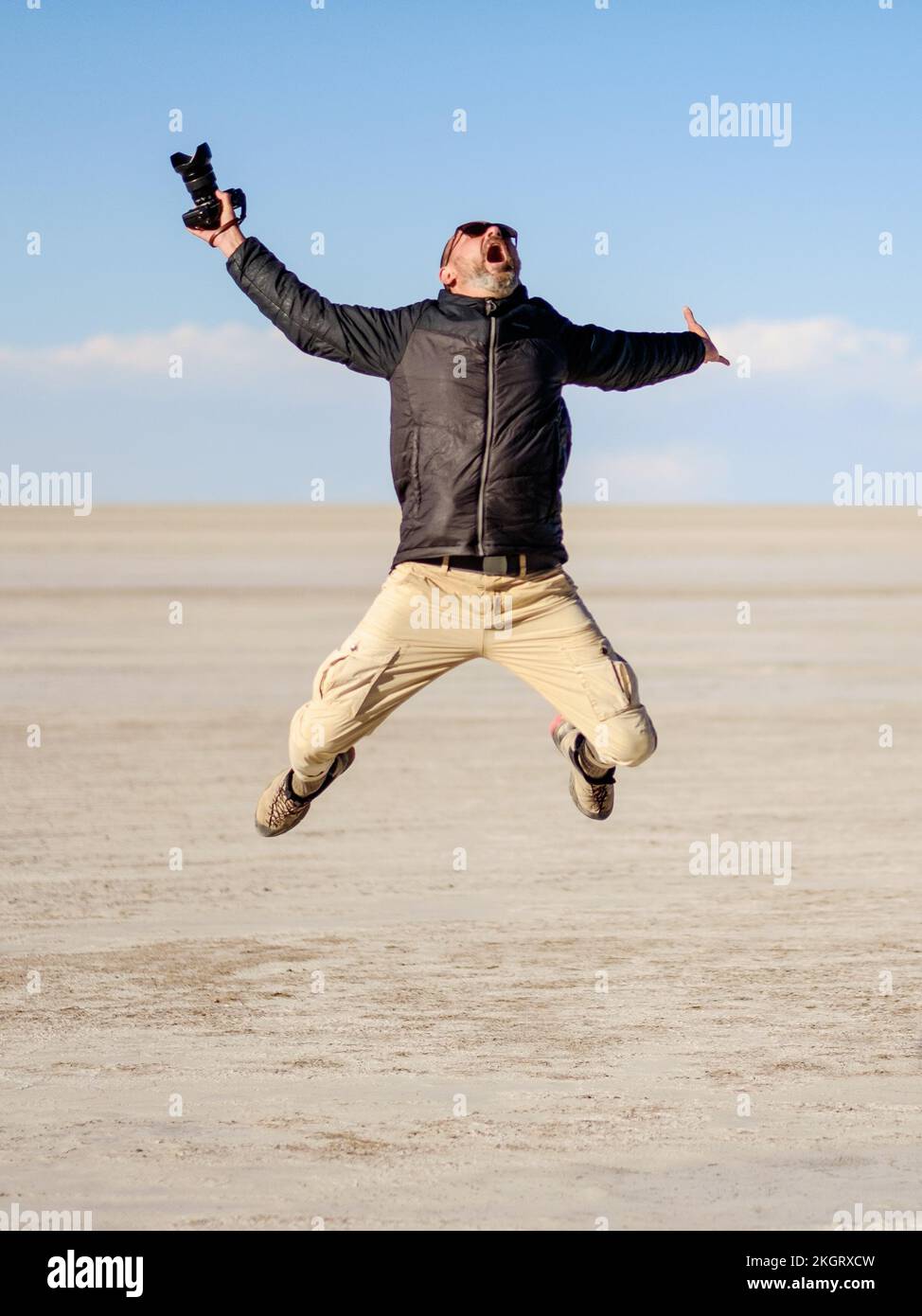 Happy man holding a camera jumping on the Salar de Uyuni (Uyuni Salt ...