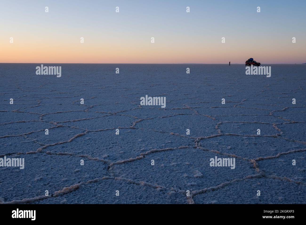 Off-road vehicle and people walking in the distance on the Salar de ...