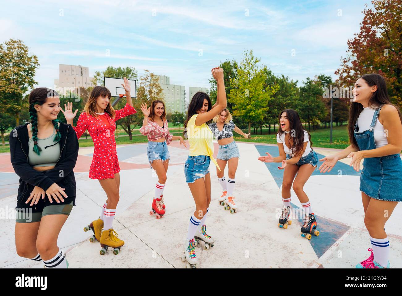 Happy friends in roller skates dancing at sports court Stock Photo - Alamy