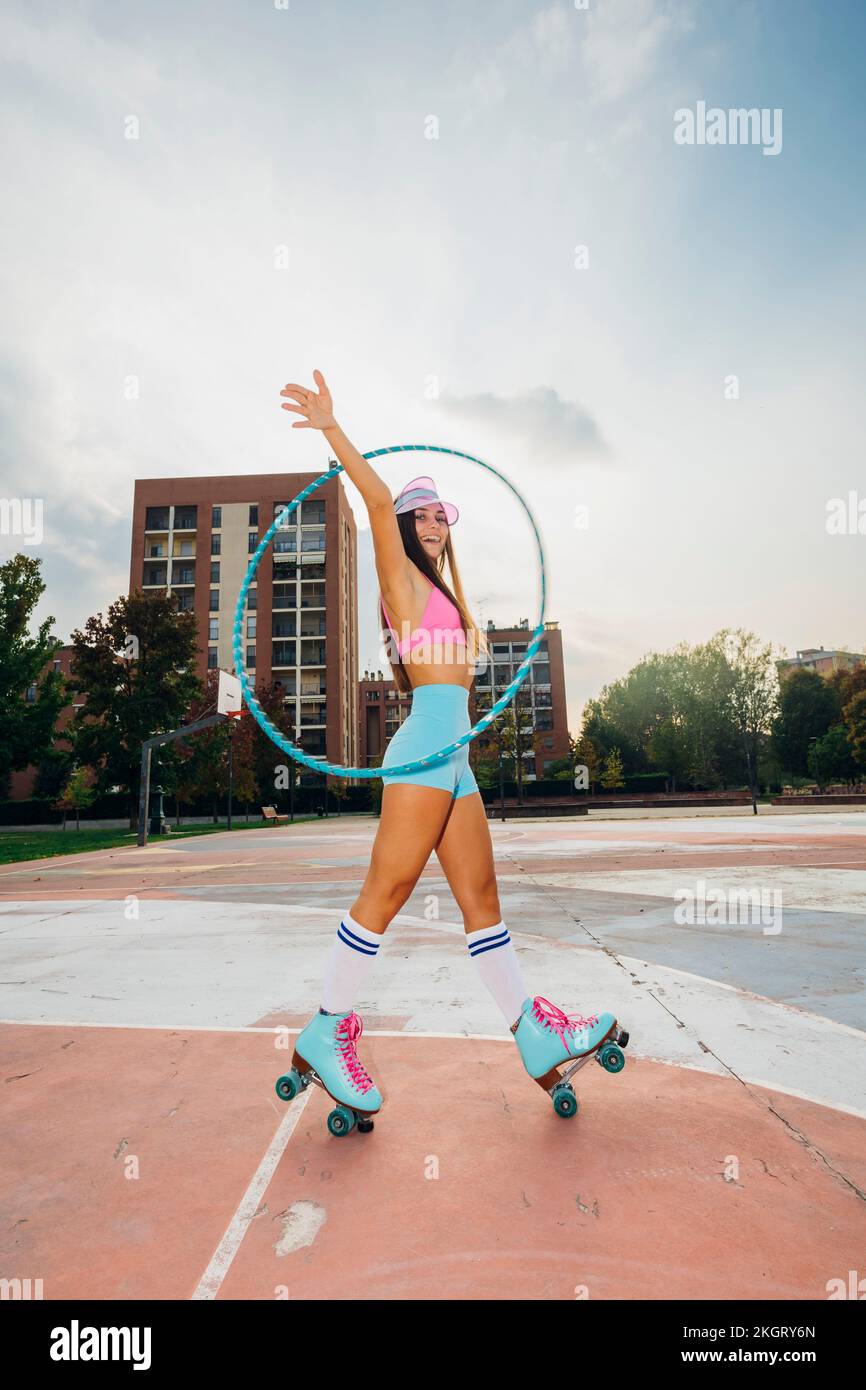 Happy woman practicing roller skating with hoop at sports court Stock ...