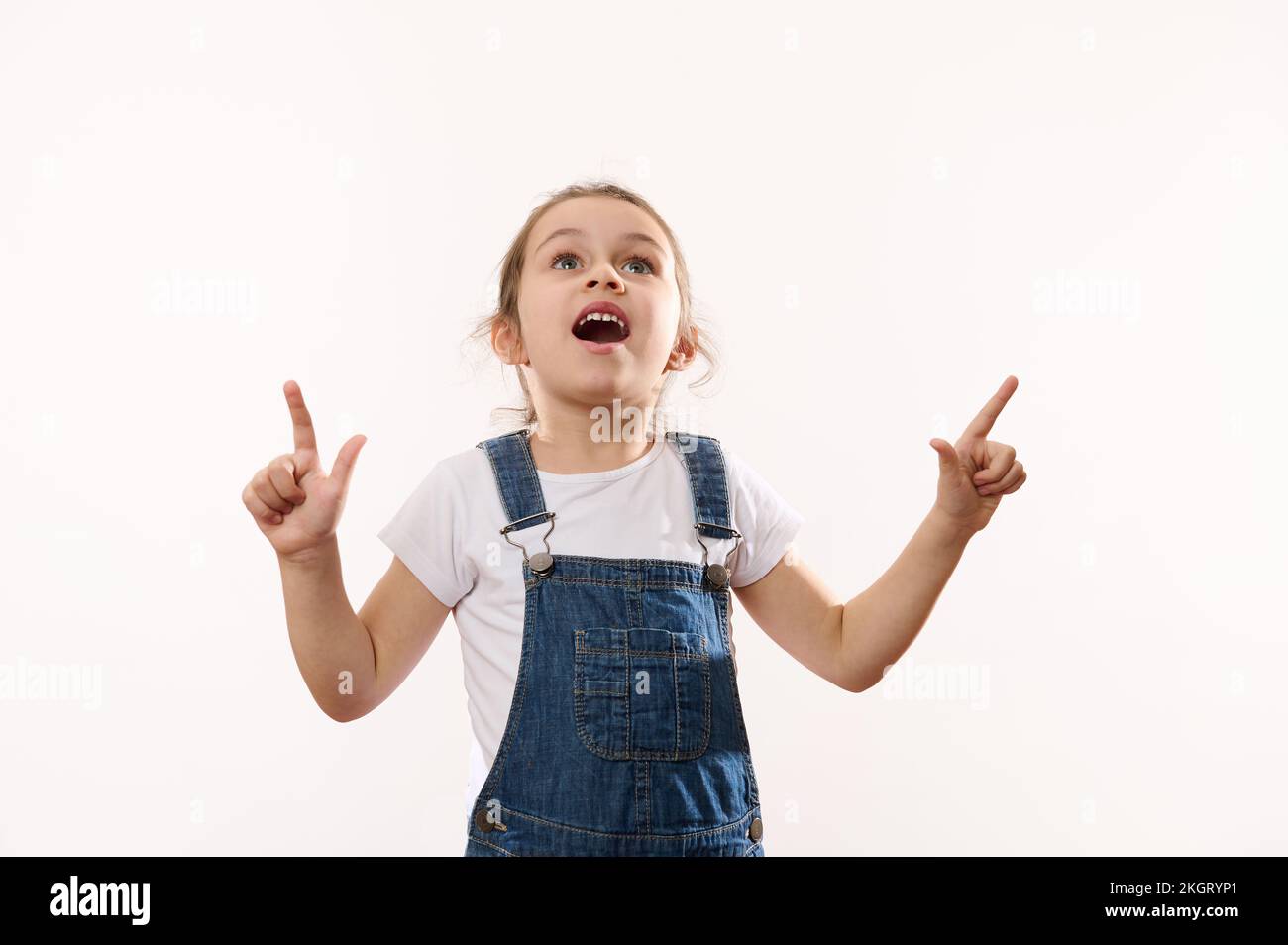 Beautiful overjoyed baby girl looks up and points with her finger at ...
