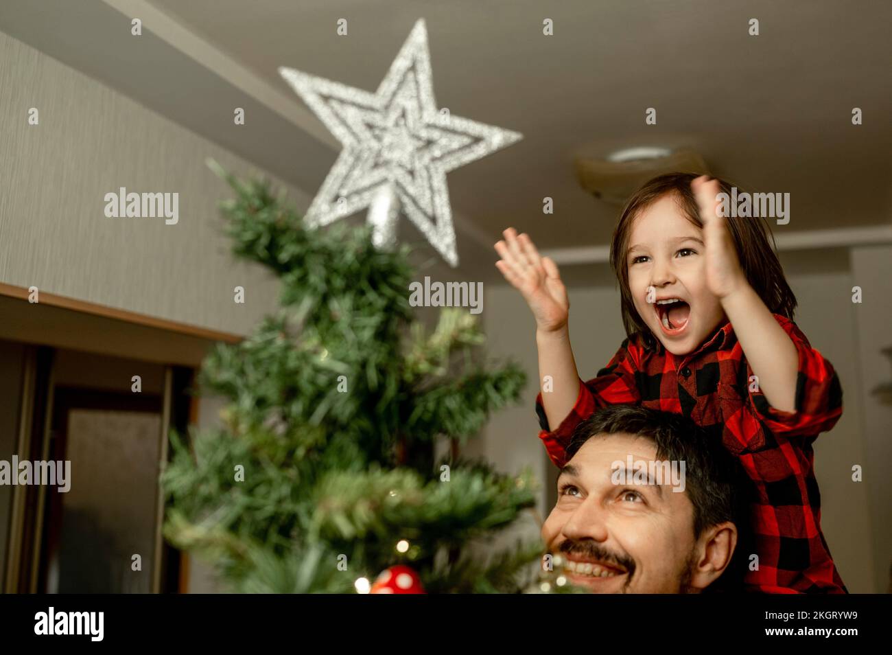 Happy son screaming looking at Christmas tree with father at home Stock ...