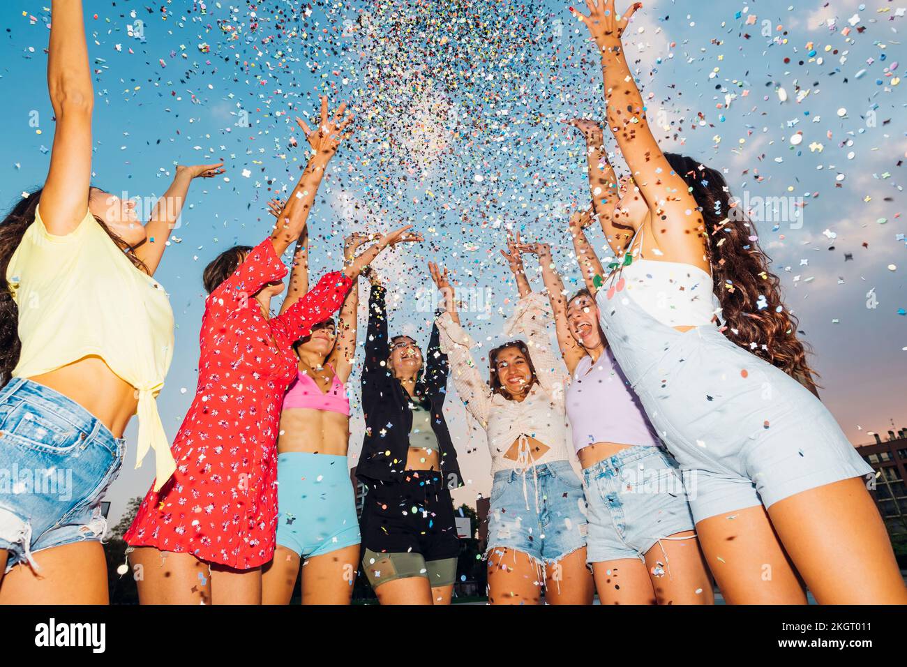 Happy friends throwing confetti under sky at dusk Stock Photo - Alamy