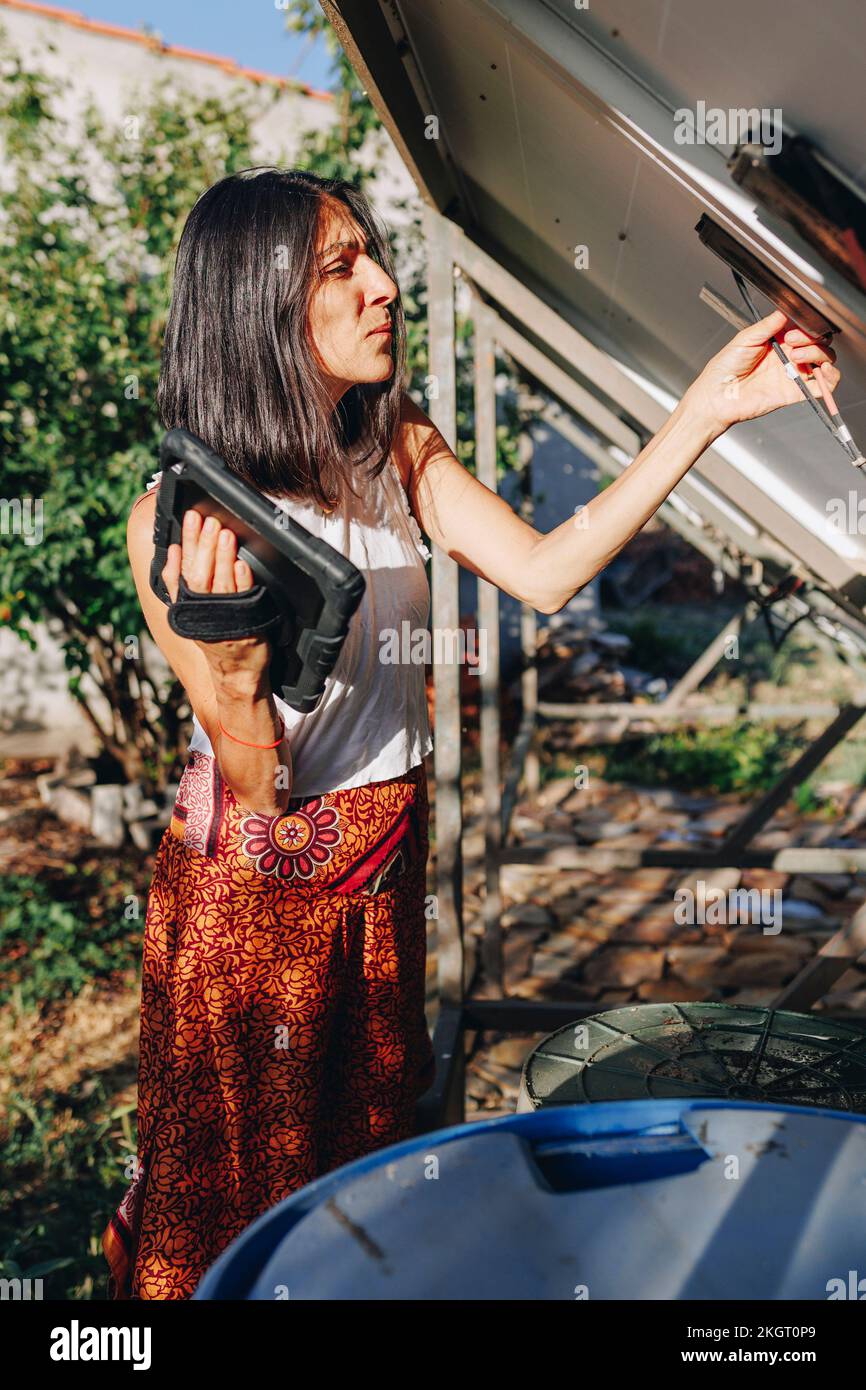 Mature woman adjusting cable of solar panels in backyard Stock Photo ...