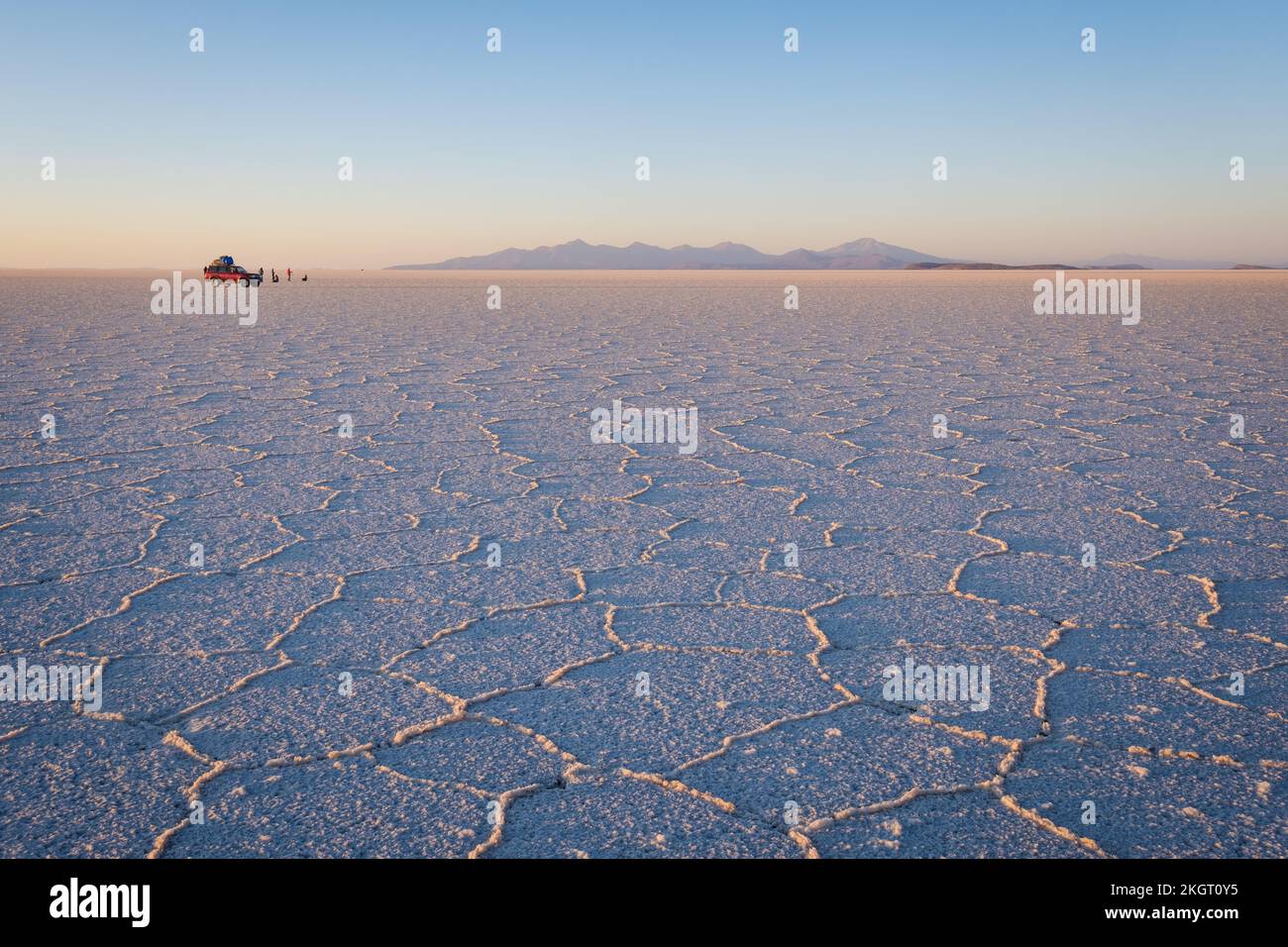 Off-road vehicle and people walking in the distance on the Salar de ...
