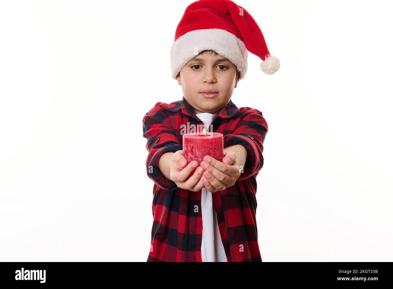 Adorable Caucasian boy in Santa hat, holding a lit red candle to the ...