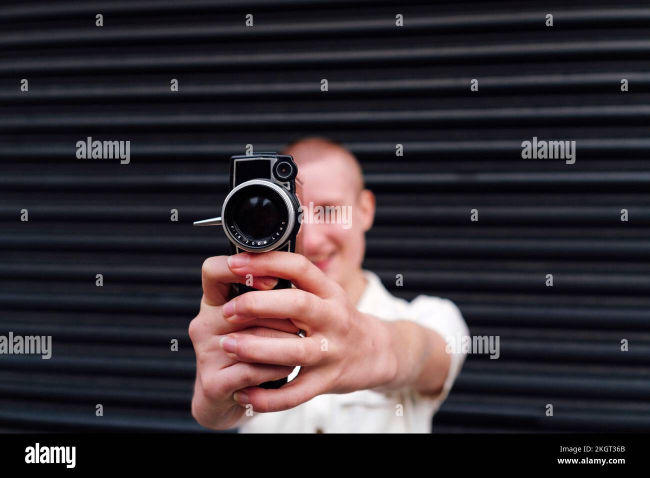 Non-binary person holding video camera in front of shutter Stock Photo ...
