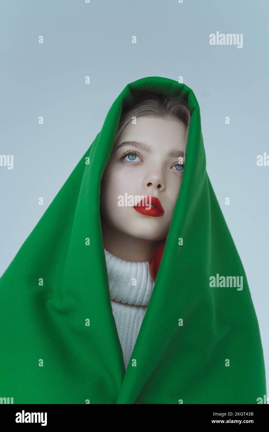 Thoughtful girl wrapped in green velvet cloth against white background ...