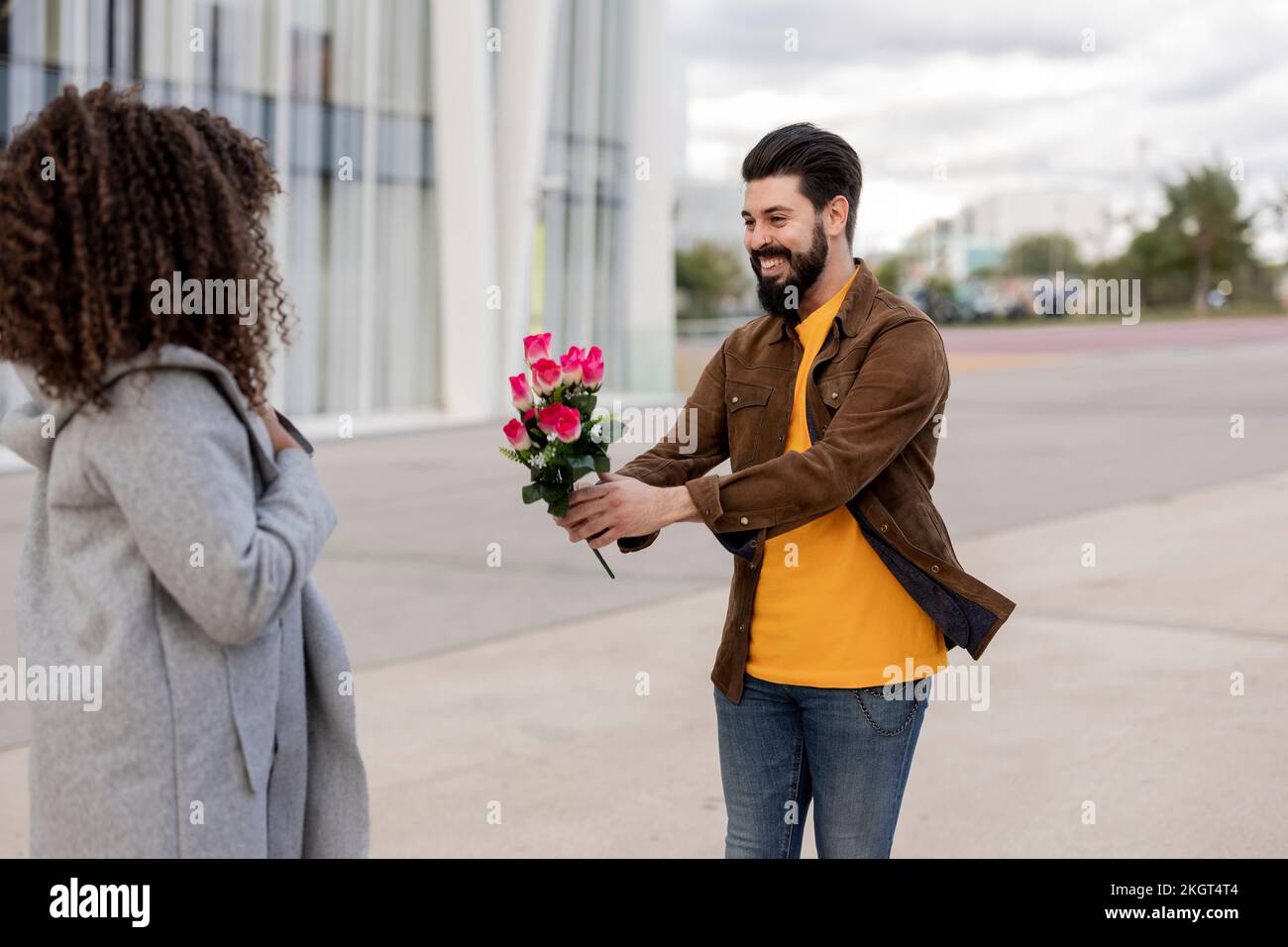 Happy young man giving bouquet of flowers to woman at footpath Stock ...