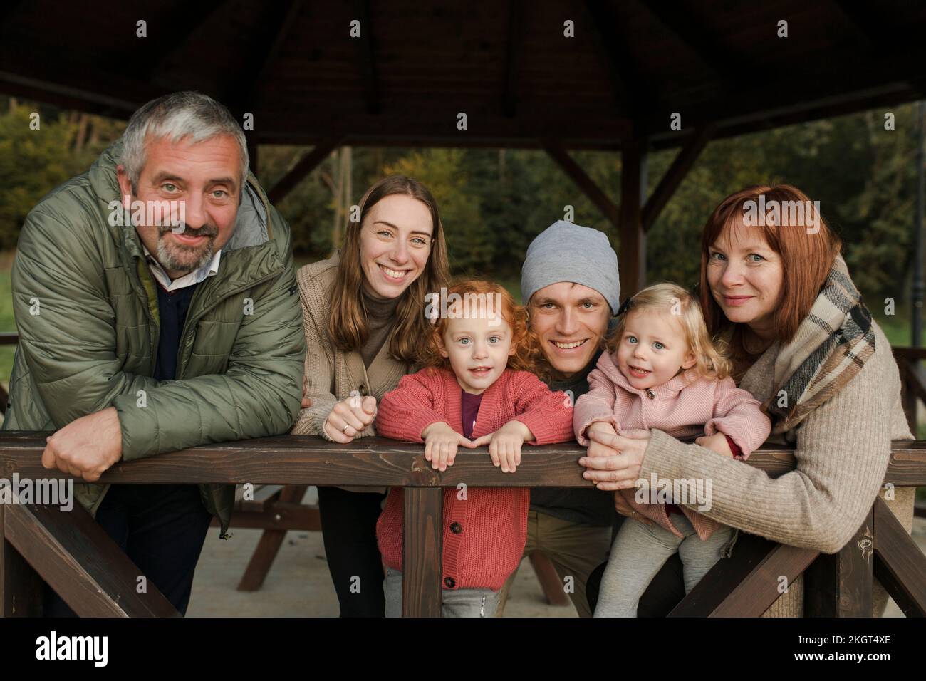 Happy family in warm clothing leaning on railing Stock Photo - Alamy