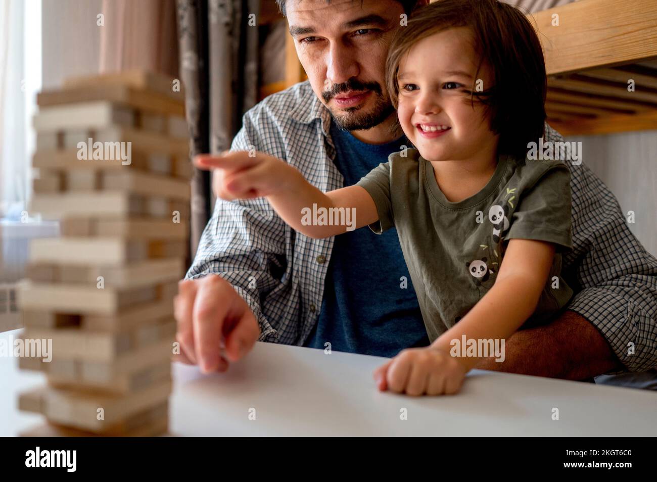 Curious boy playing block removal game with father at home Stock Photo ...