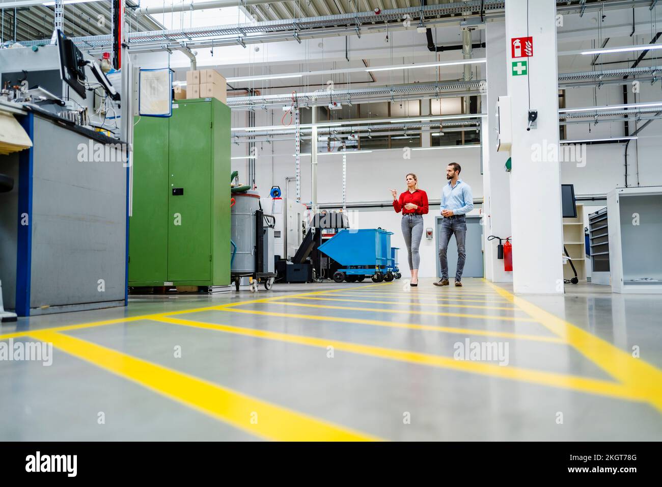 Businesswoman walking with colleague on markings in production hall at ...