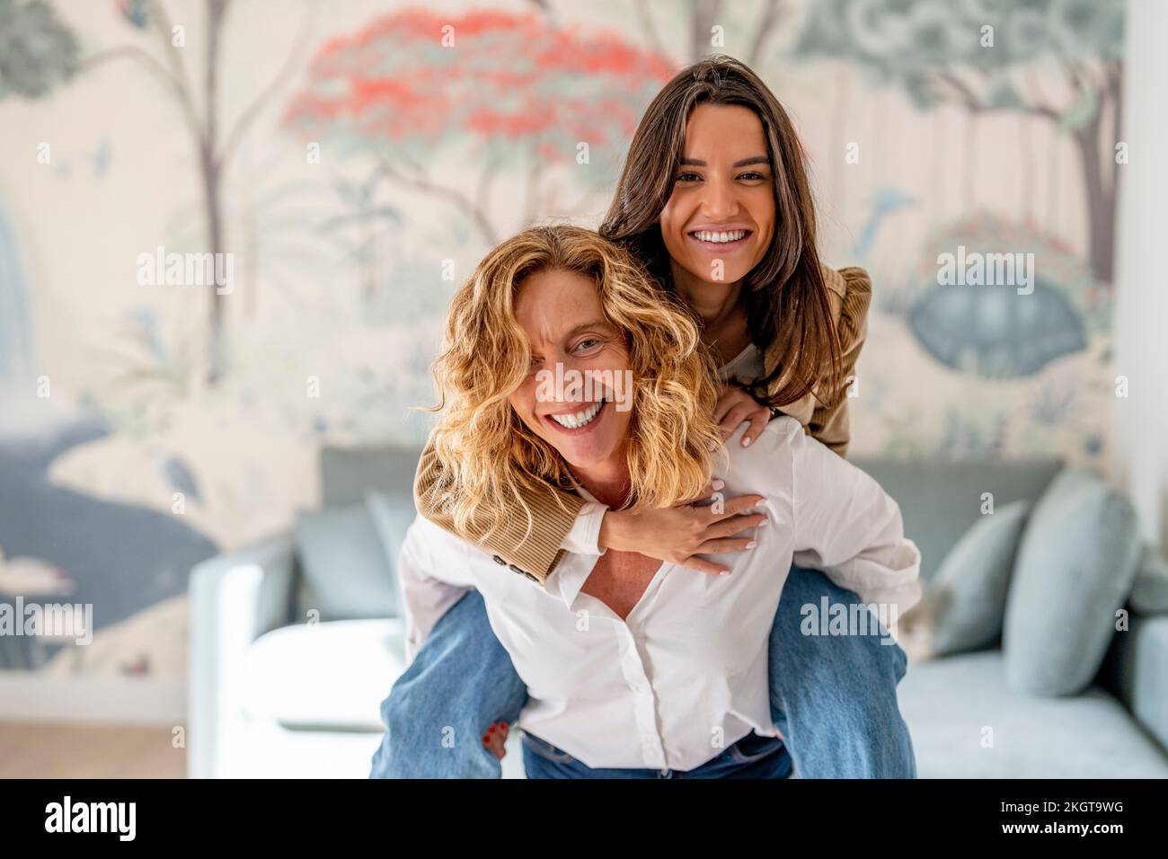 Happy mother giving piggyback ride to daughter at home Stock Photo - Alamy