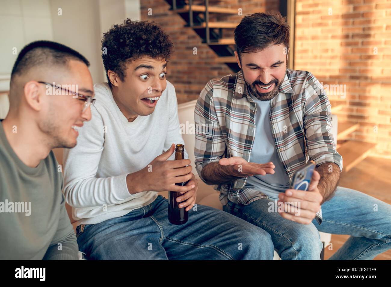 Three merry men viewing photos on the cellphone Stock Photo - Alamy