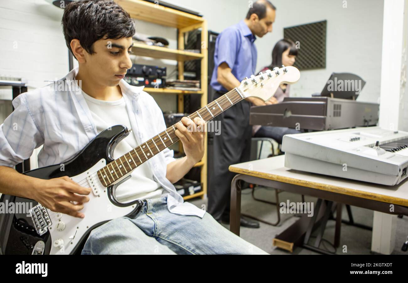 Music Students: Playing Together. A young guitarist practicing chords ...