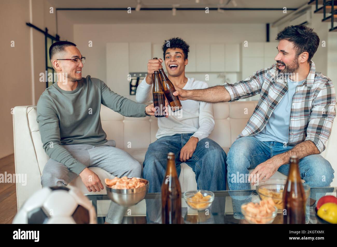 Three joyful buddies drinking to their meeting Stock Photo - Alamy