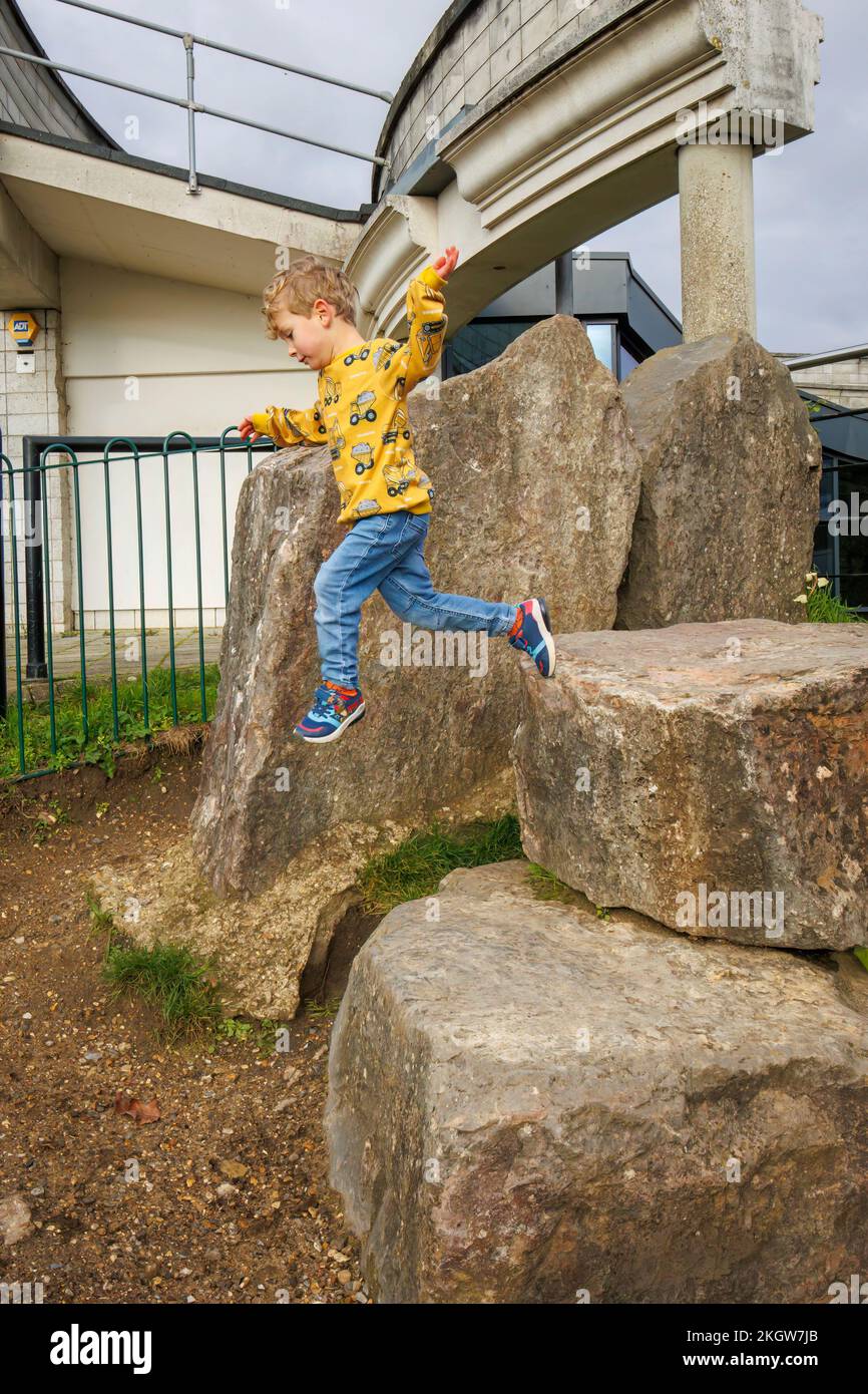 A small blonde caucasian boy (aged 4) wearing a yellow top and blue ...