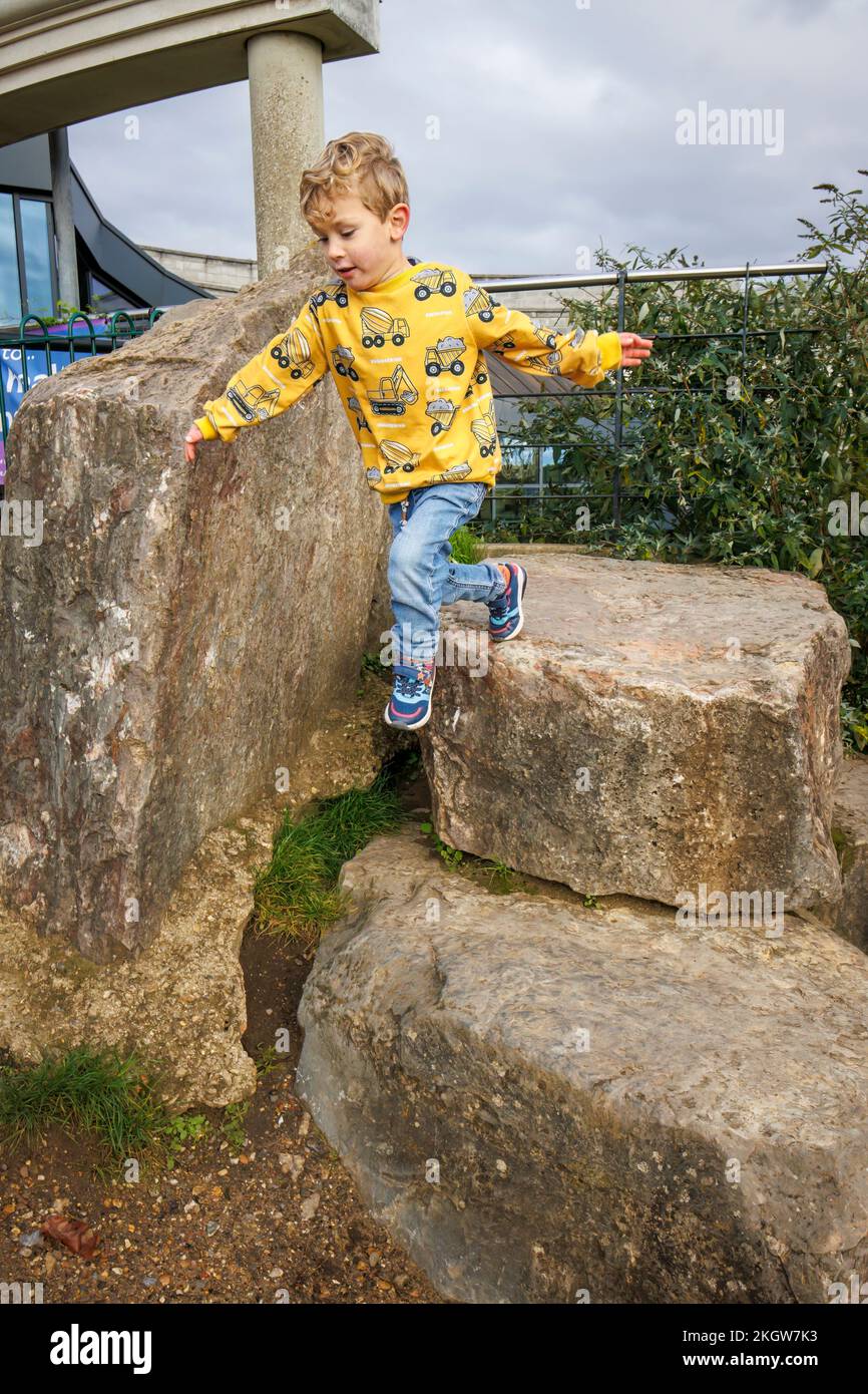 A small blonde caucasian boy (aged 4) wearing a yellow top and blue ...