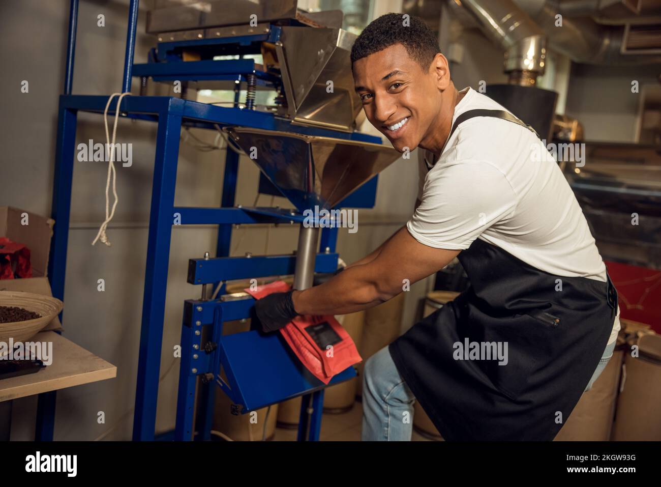 Cheerful worker sealing a coffee bag with the heat sealer Stock Photo ...