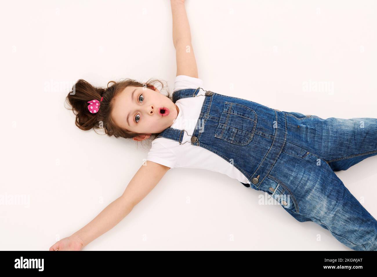 Top view happy little child girl, wearing blue denim overalls ...