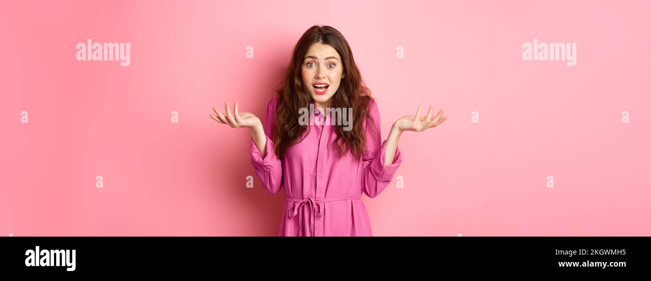 Confused young brunette woman with nervous face expression, raising ...
