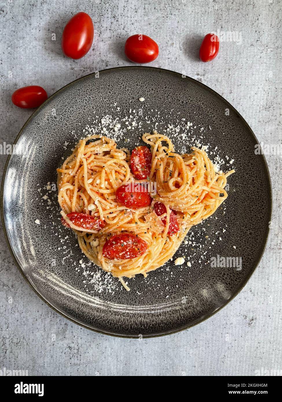 A top view shot of a spaghetti with tomato on a grey plate Stock Photo ...