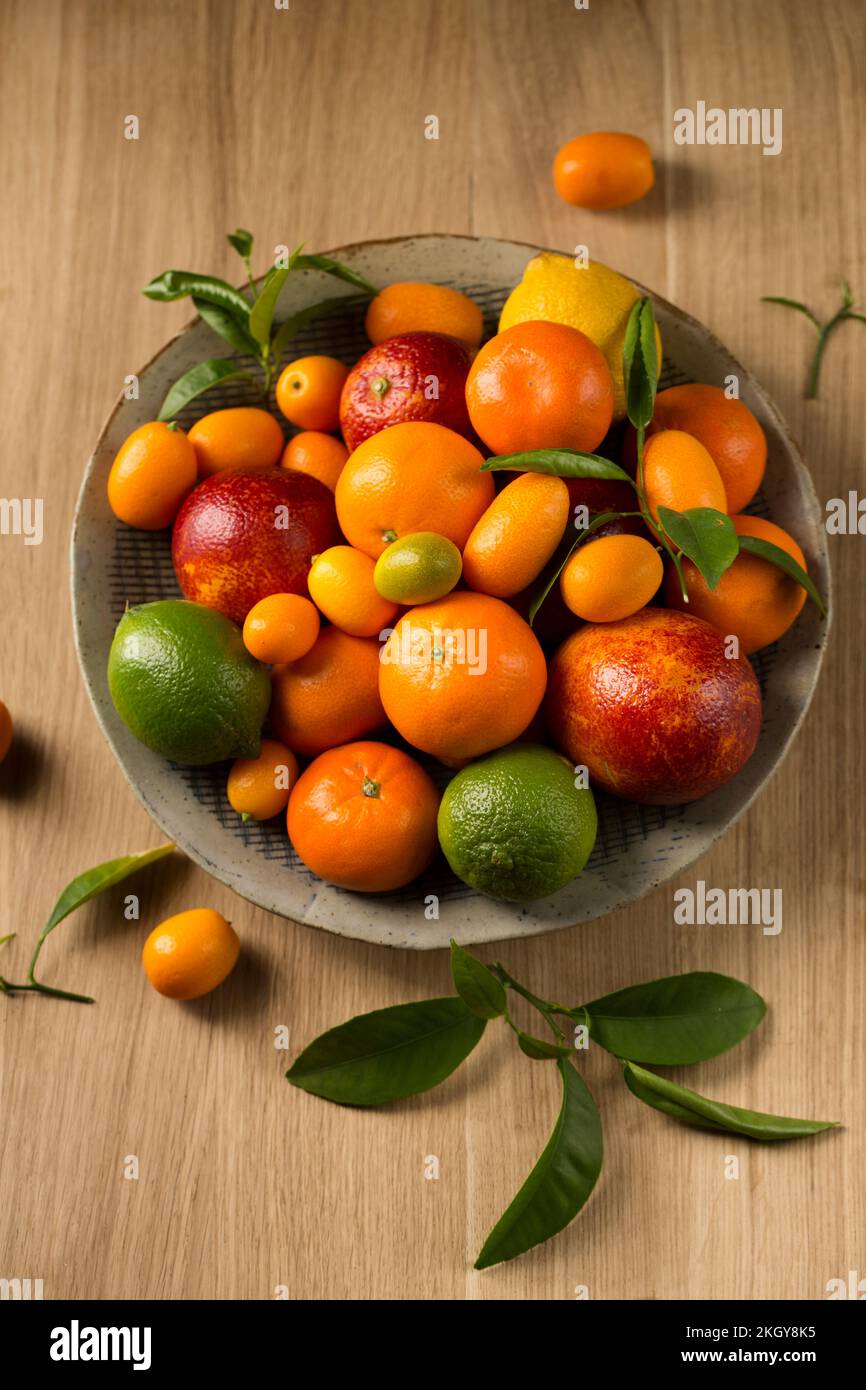 A large plate of juicy citrus fruits on a wooden table Stock Photo - Alamy