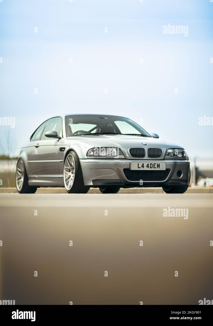 A vertical shot of grey modern BMW M3 CSL on the road with blue sky in ...