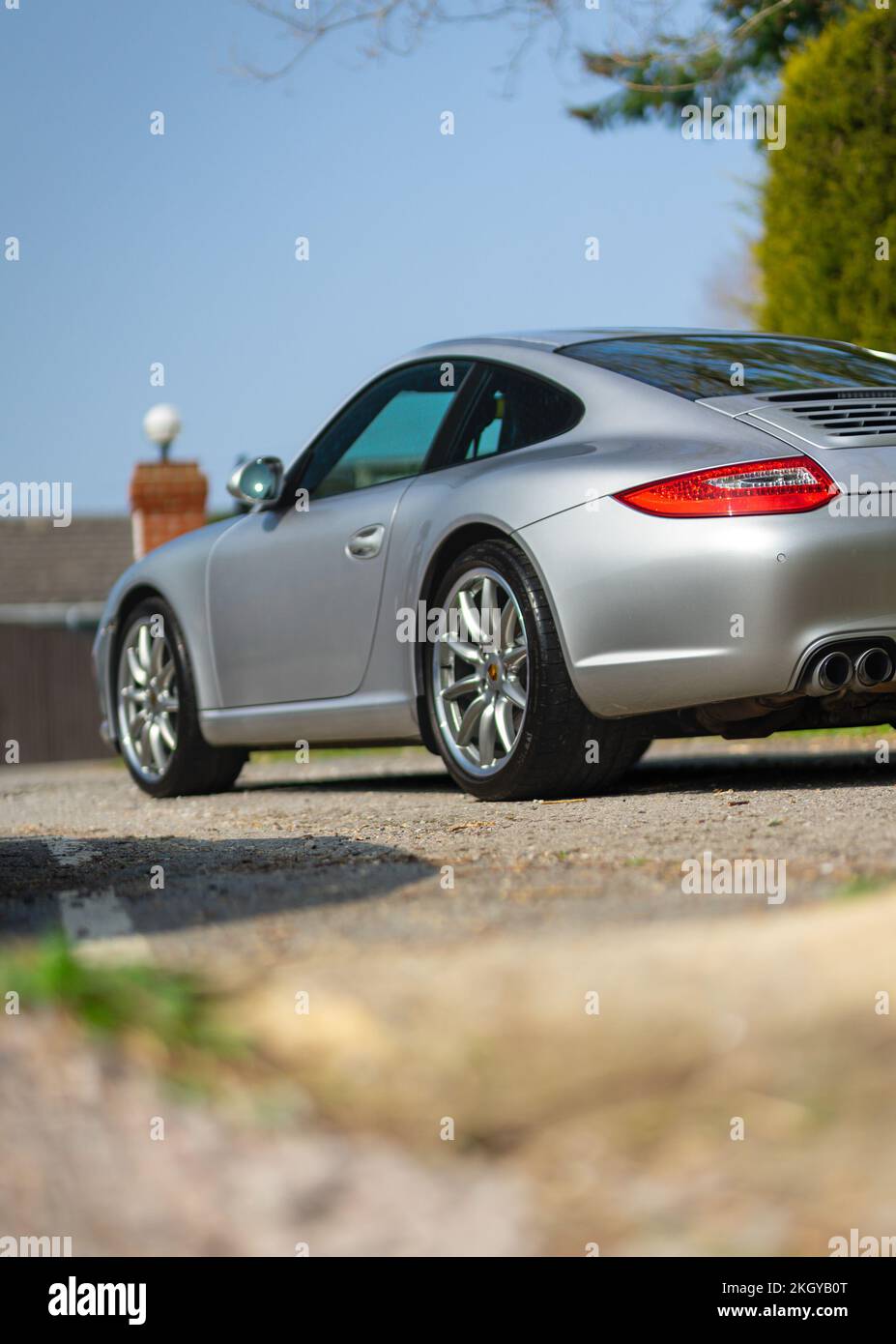 A vertical shot of the back of grey modern Porsche 911 parked on the ...