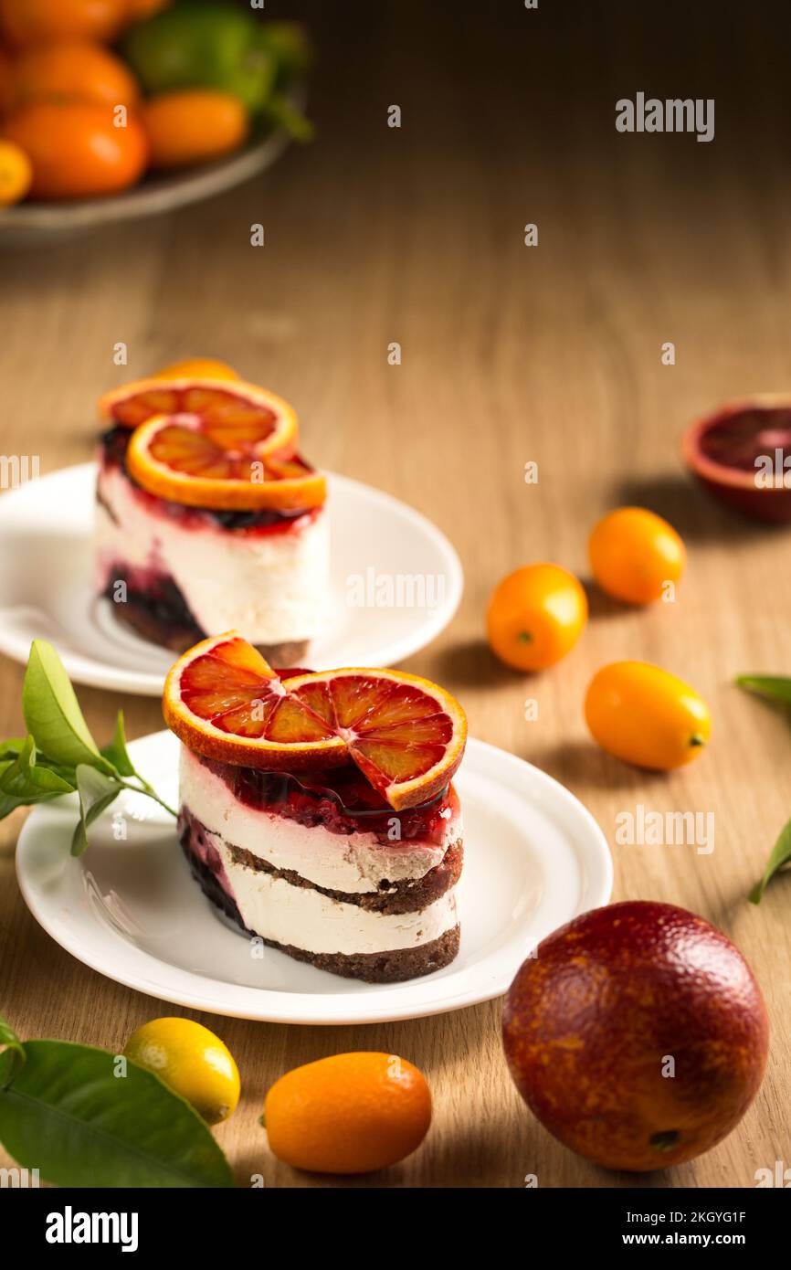 Panna cotta dessert with berry jelly and red orange on a white plate ...