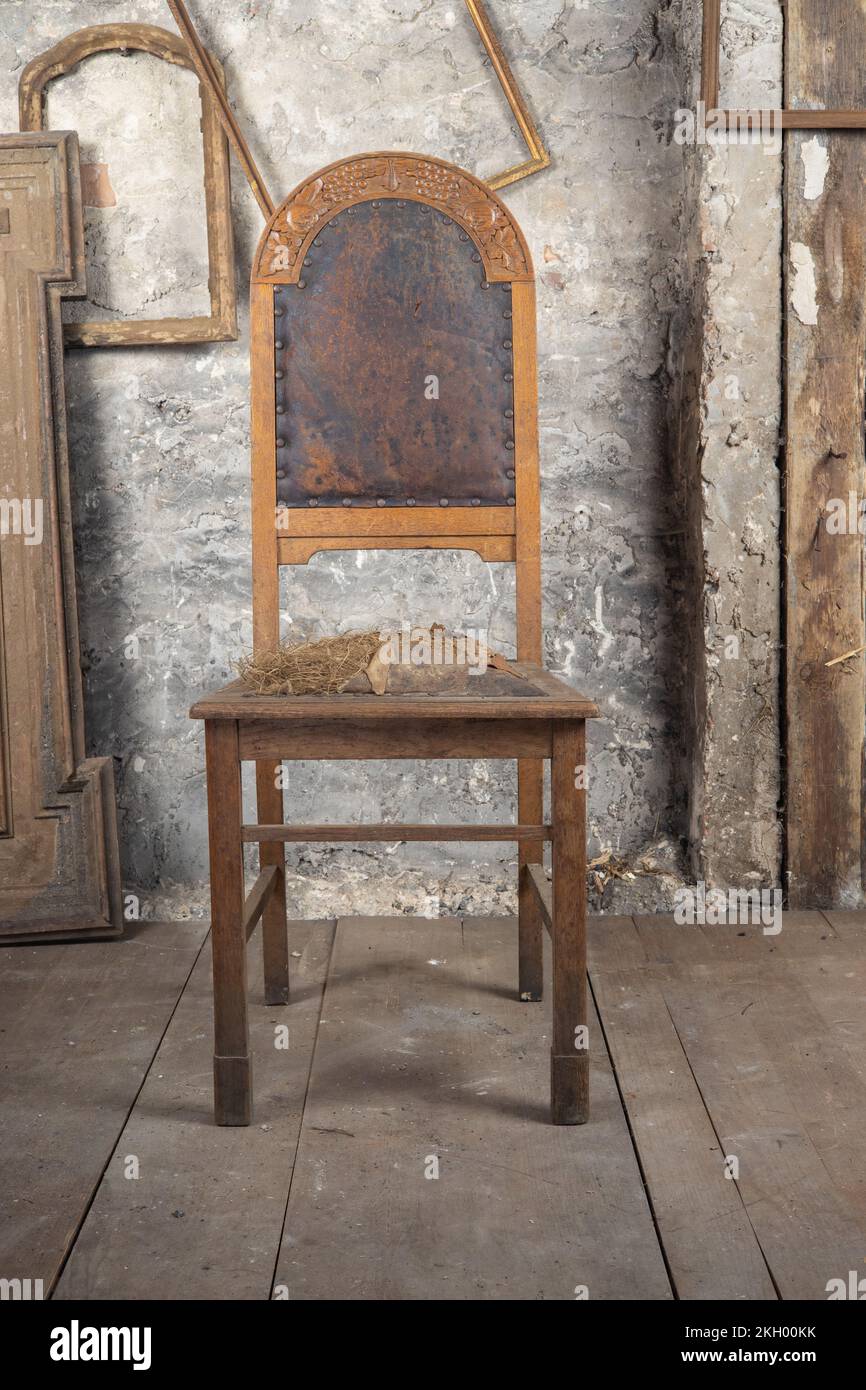 An old oak chair stands in a dirty room, on the old floor next to other ...