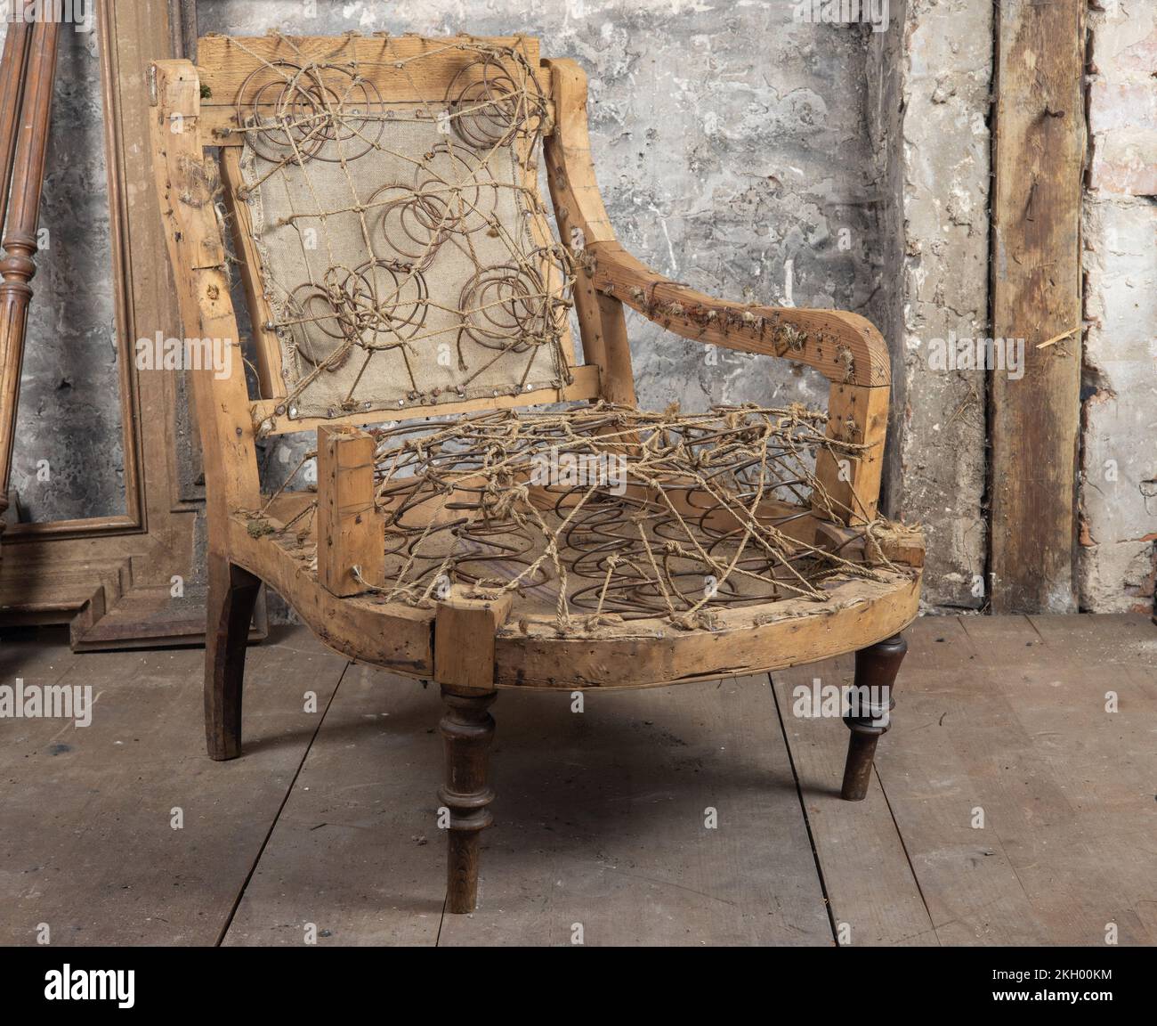 Defective old broken armchair on the old floor next to other vintage ...