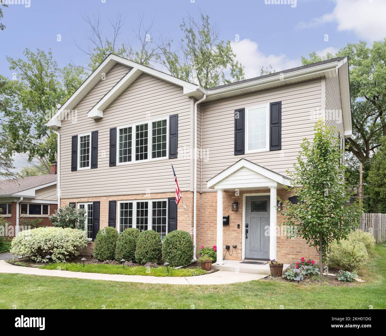 A two story suburban home with brick and tan vinyl siding and a ...
