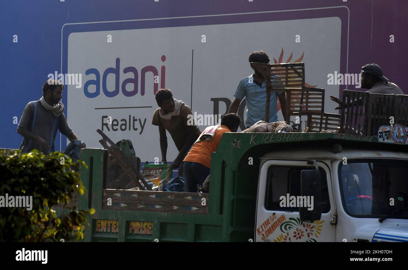 People are seen working on a truck next to the Adani logo on a poster ...