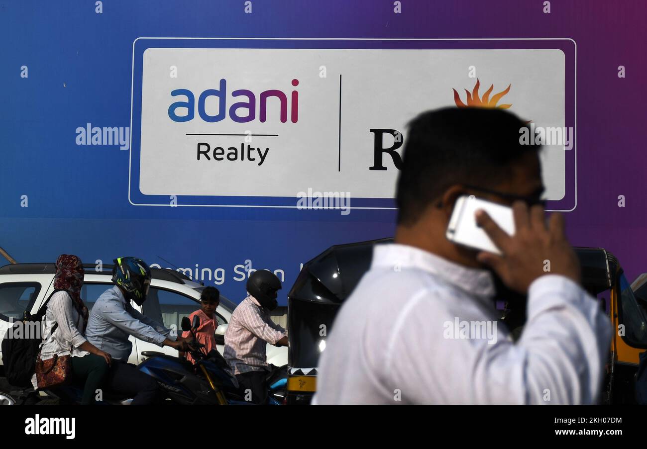 A man talking on his phone walks past the Adani branding on a poster in ...