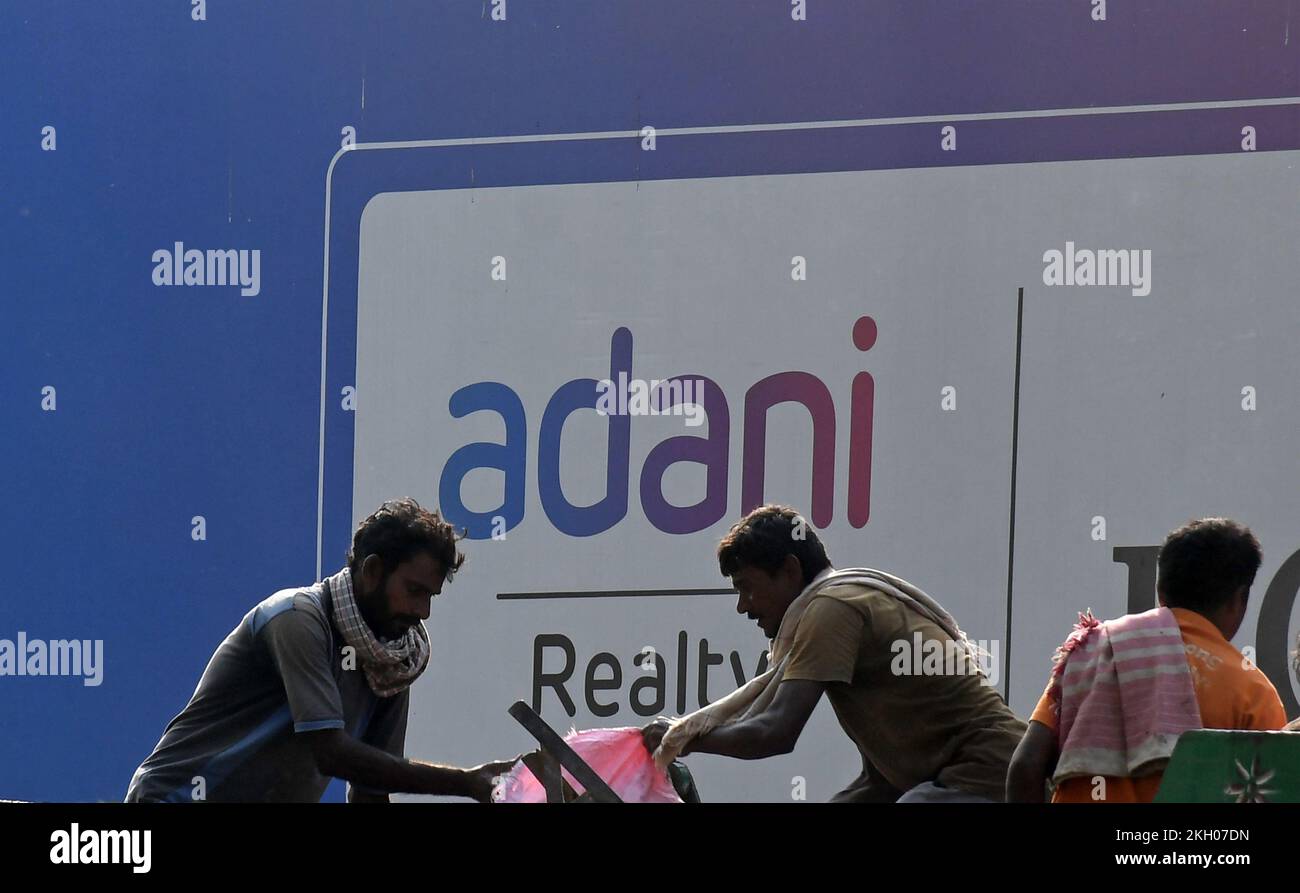 People are seen working on a truck next to the Adani logo on a poster ...